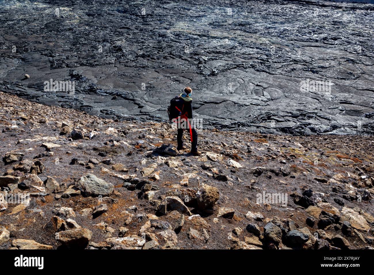 Female tourist with backpack standing on top of the molten basalt rocks ...