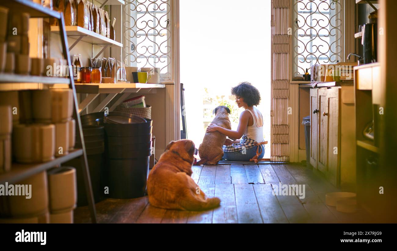 Woman With Pet Dogs Sitting In Doorway Of Sustainable Plastic Free ...