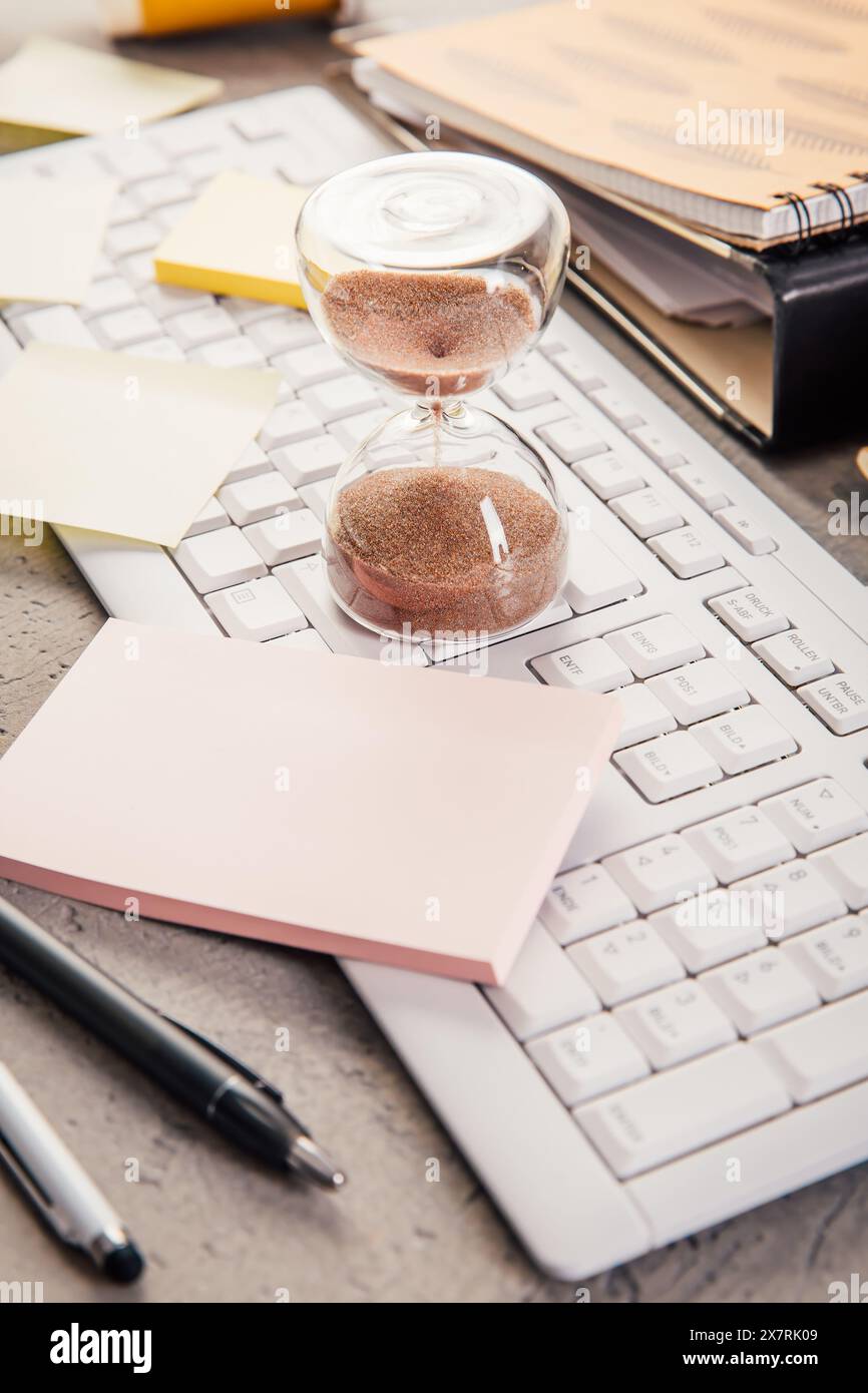 Crop of hourglass on home office table count measure time. Workplace of ...