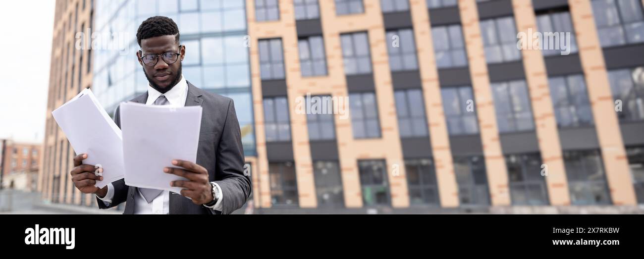 Young black man in suit checking reports outdoors Stock Photo - Alamy