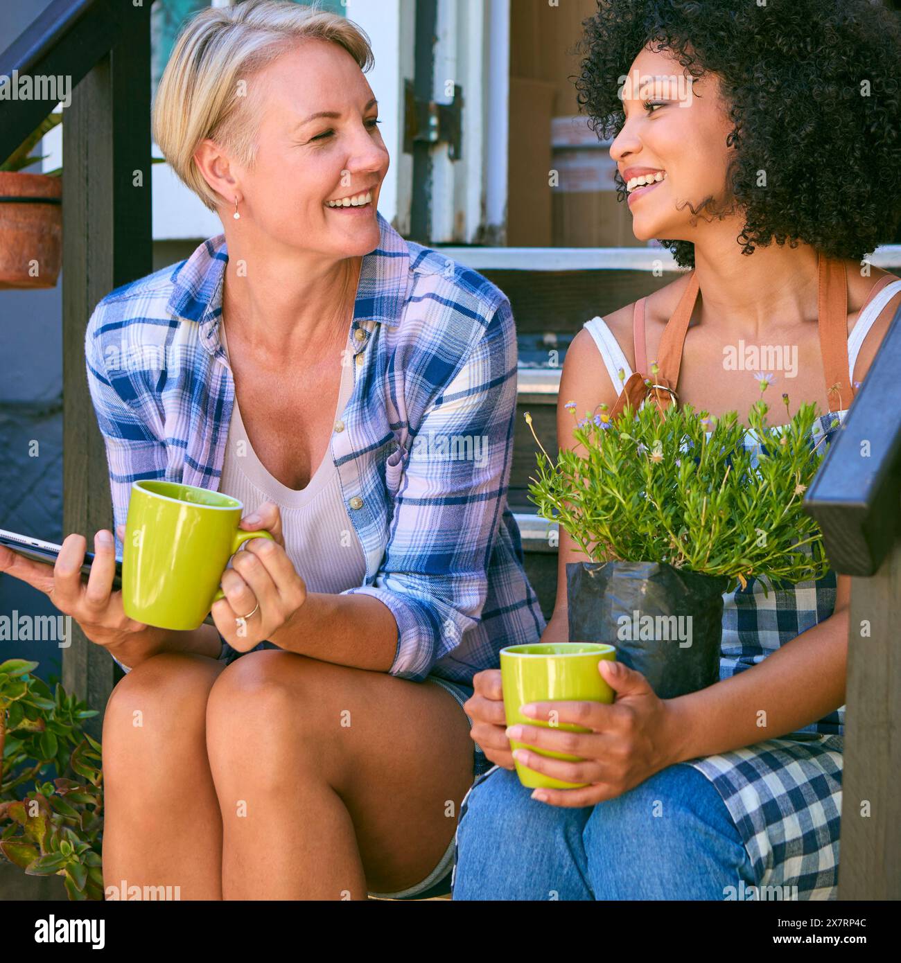 Female Staff With Digital Tablet Sitting On Steps Working In Garden ...