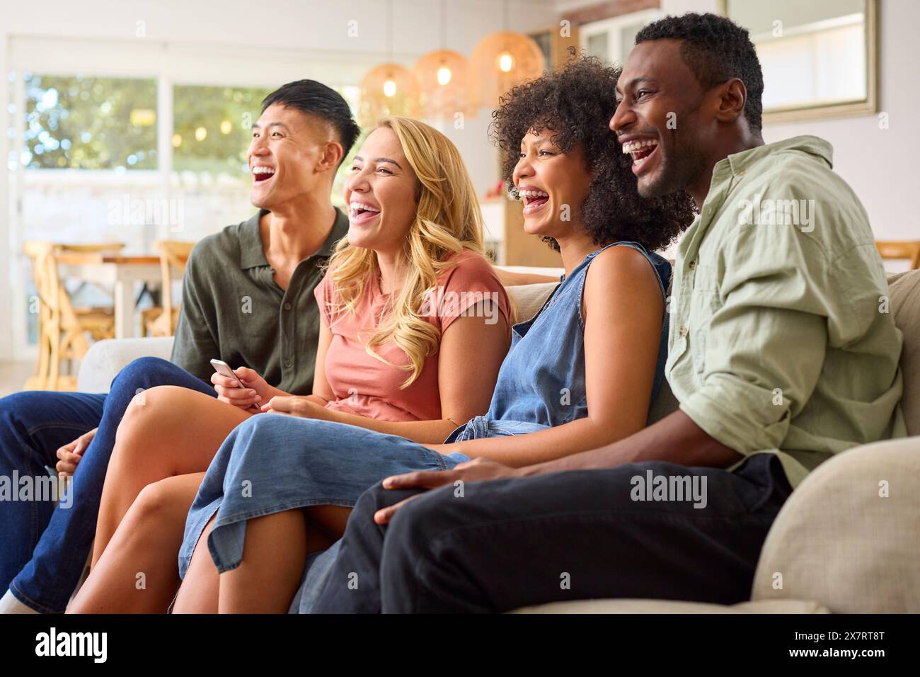 Group Of Multi-Racial Friends Sitting On Sofa Laughing Watching Movie ...