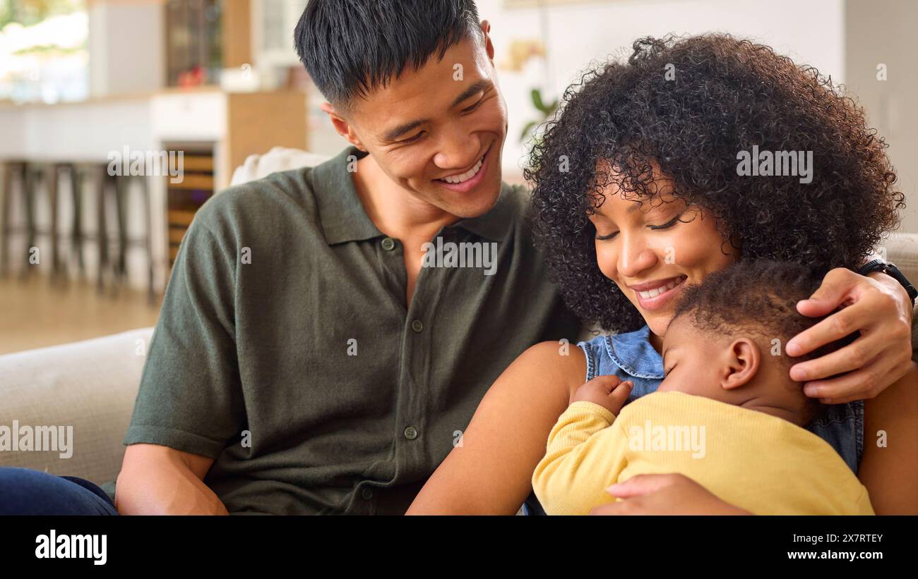 Loving Family Cuddling Sleeping Baby Daughter On Sofa With Parents ...