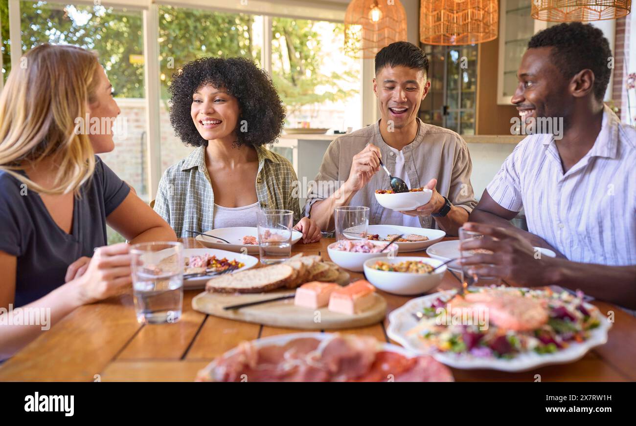 Group Of Multi-Racial Friends Sitting Around Table Enjoying Meal At ...
