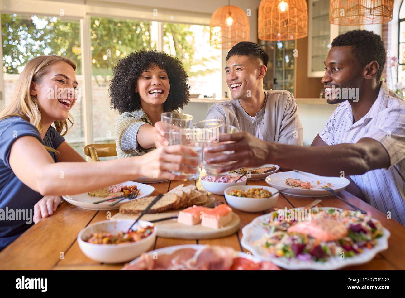Group Of Multi-Racial Friends Sitting Around Table Enjoying Meal At ...