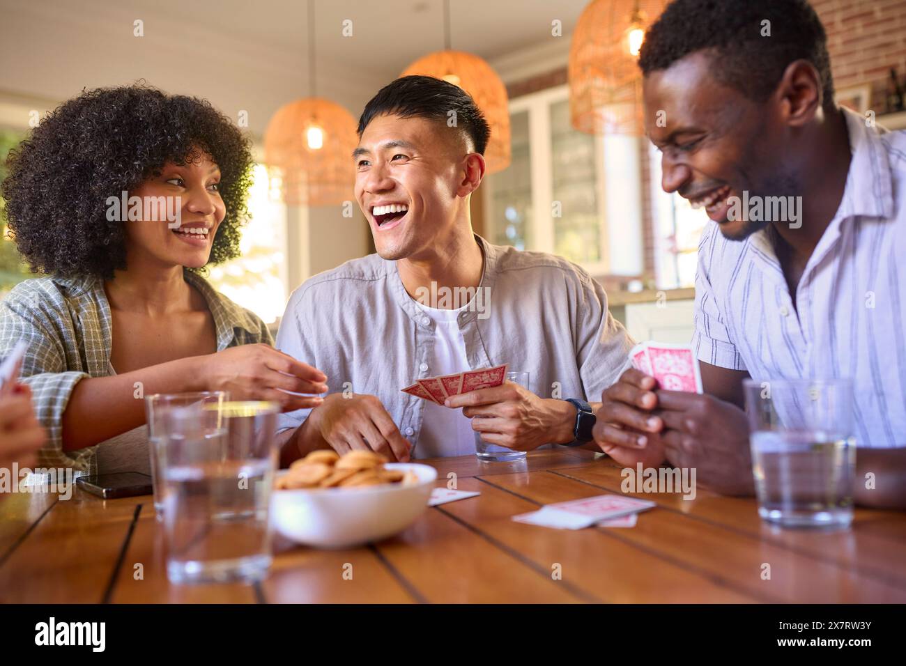 Group Of Multi-Racial Friends Sitting Around Table Playing Game Of ...