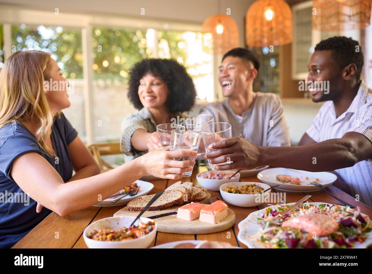Group Of Multi-Racial Friends Sitting Around Table Enjoying Meal At ...