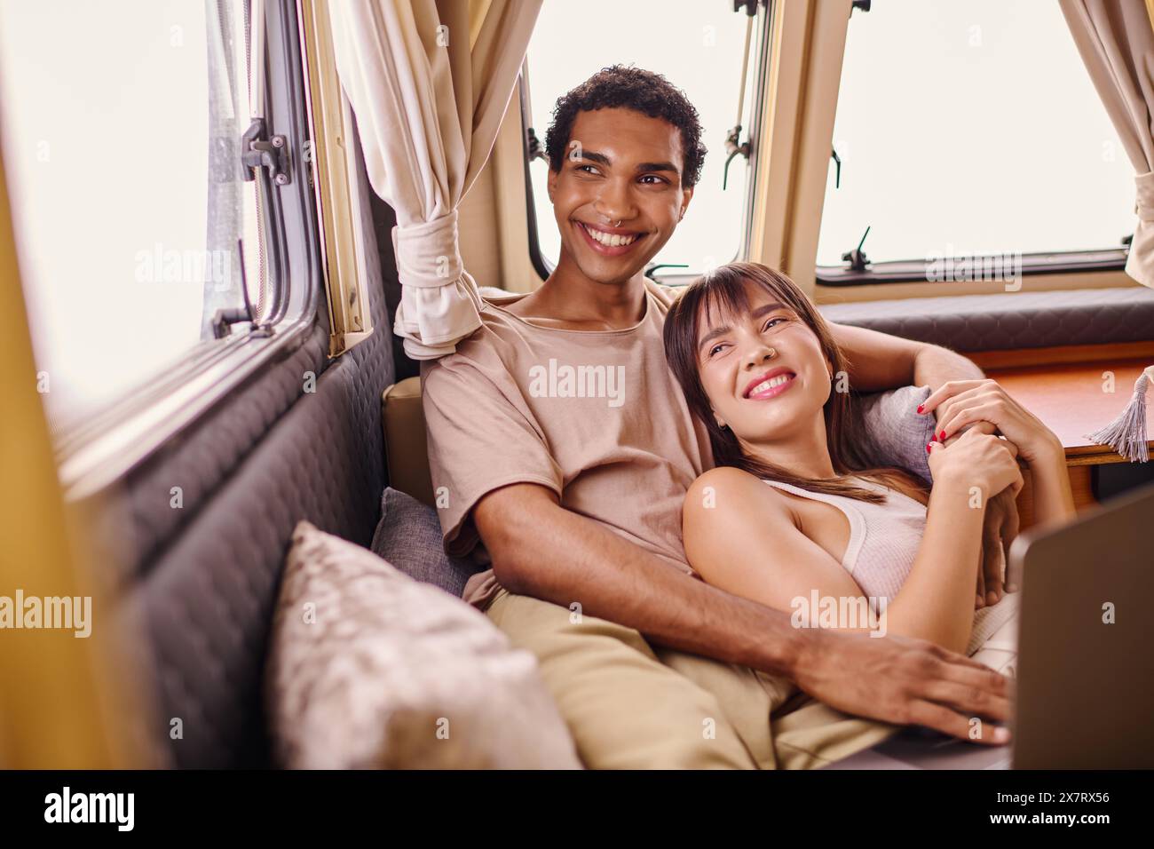 A man and woman sit side by side on a train, gazing out the window as they travel together on a ...