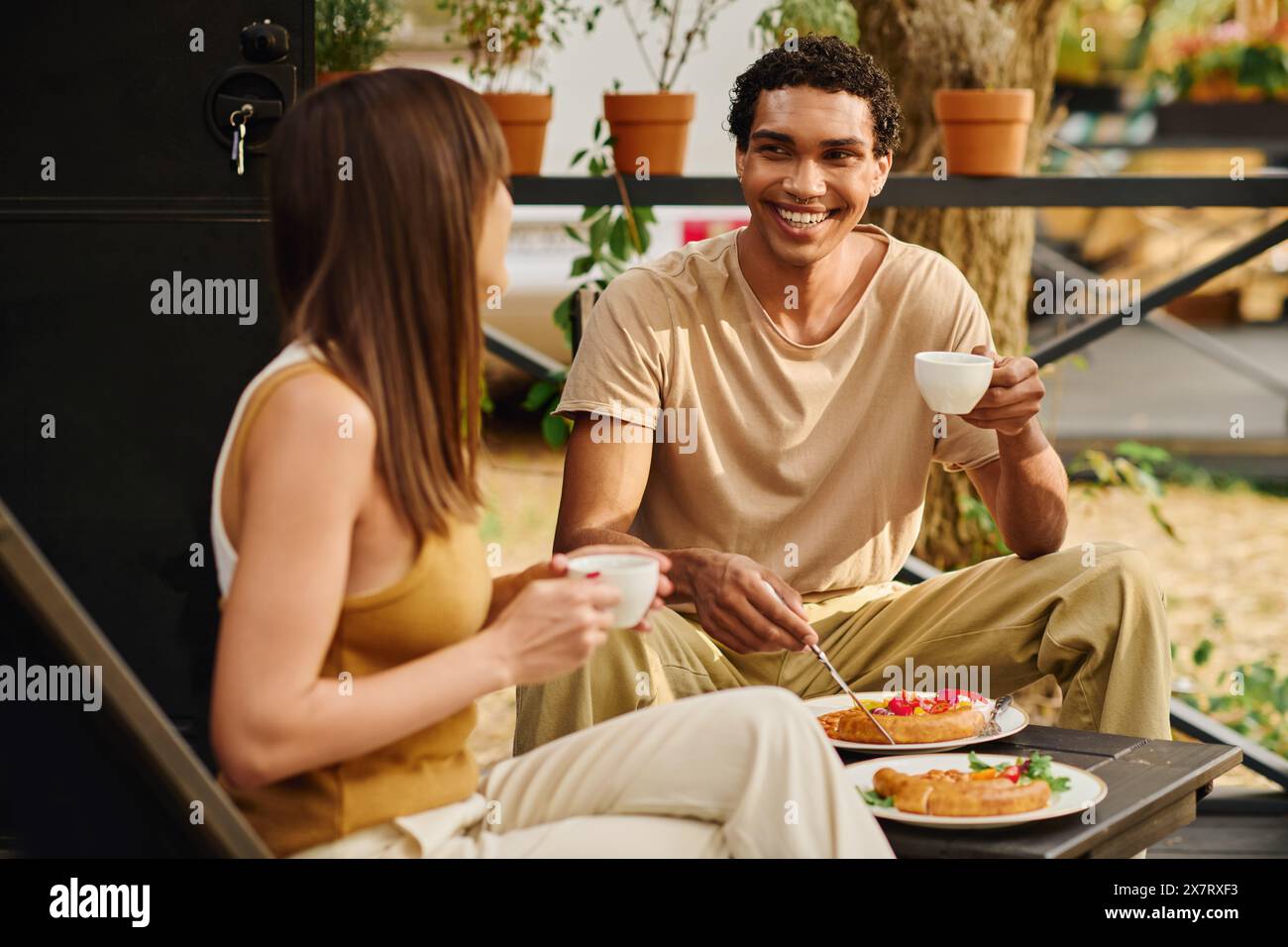 An interracial couple enjoying a meal together on a bench, savoring ...