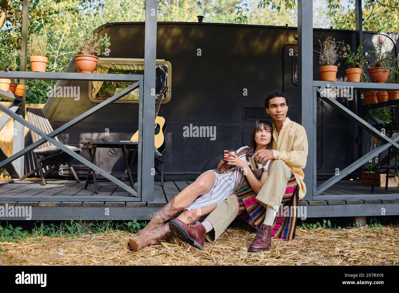 An interracial man and woman sit together on the ground, taking a ...