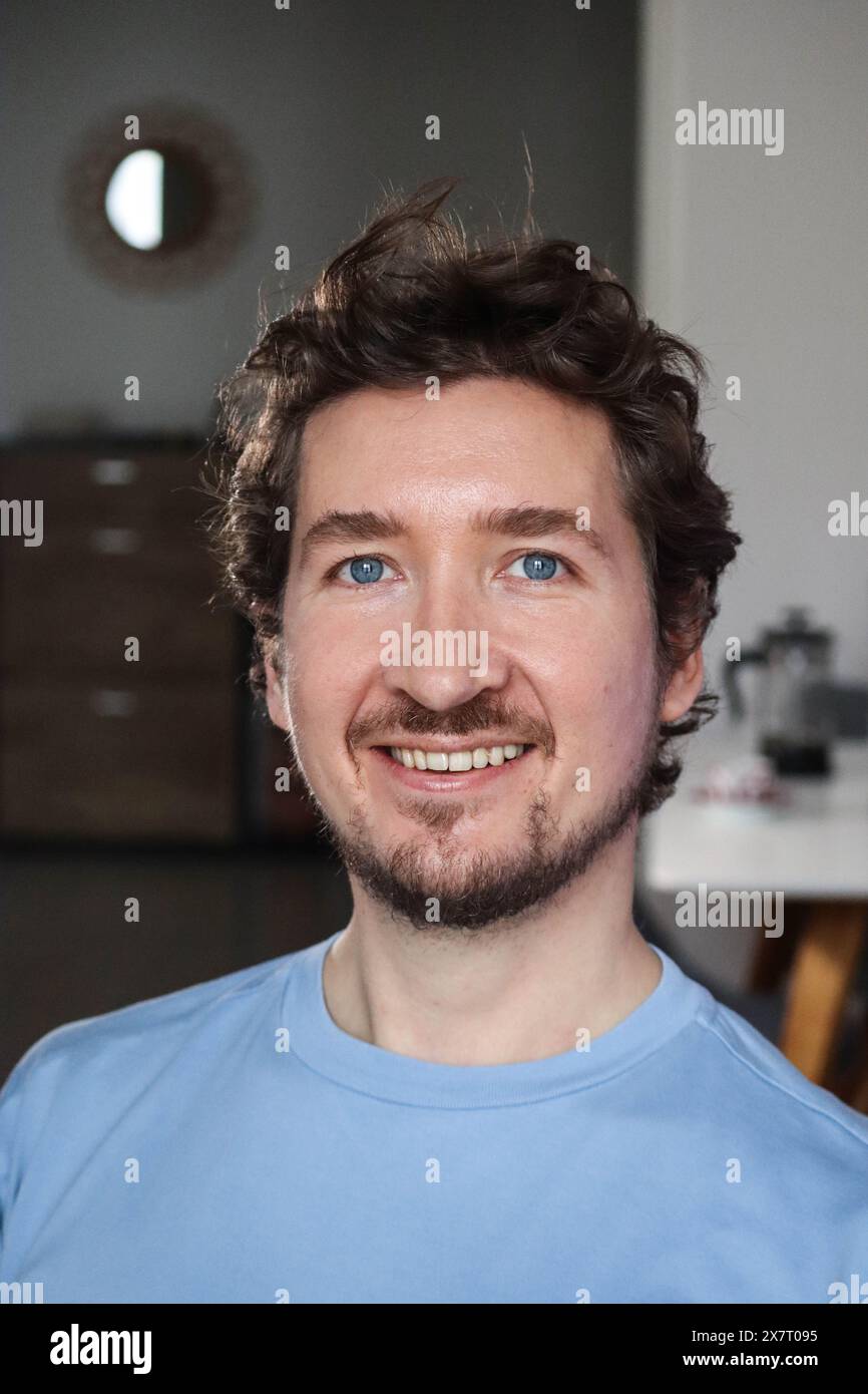 Handsome young man with blue eyes and wavy hair smiling Stock Photo - Alamy