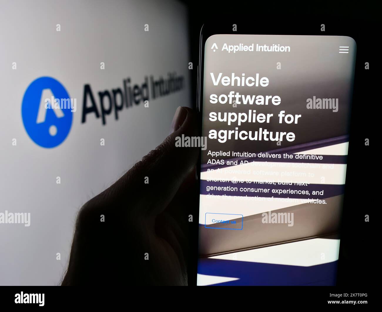 Person holding cellphone with webpage of US vehicle software company ...