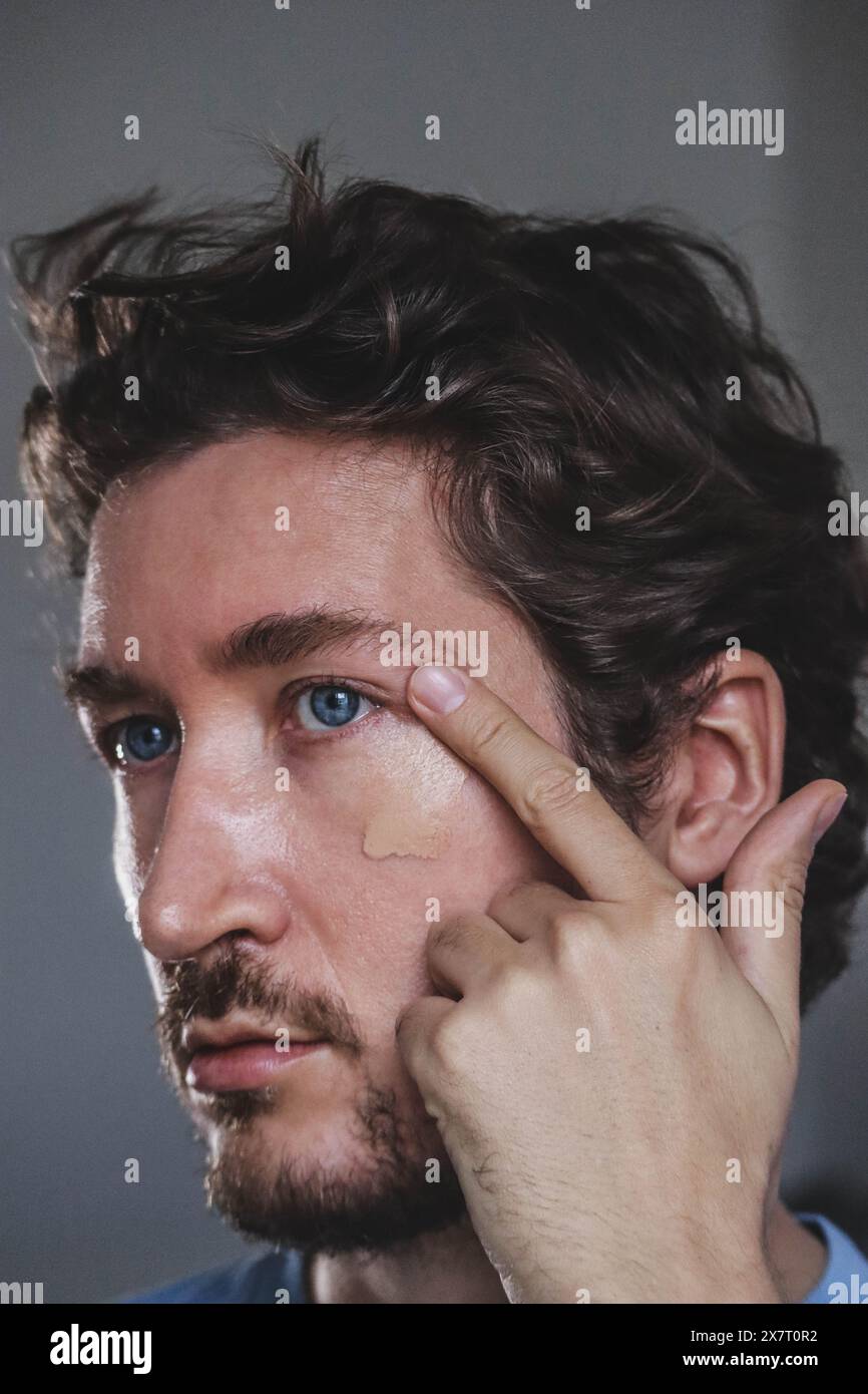 Handsome young man applying foundation to his face Stock Photo - Alamy