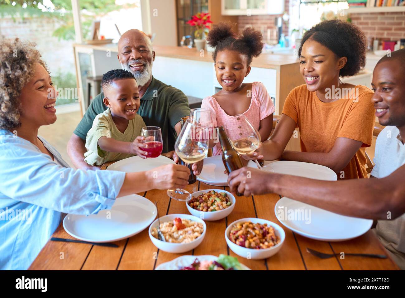 Multi-Generation Family Around Table Doing Cheers With Drinks Before ...