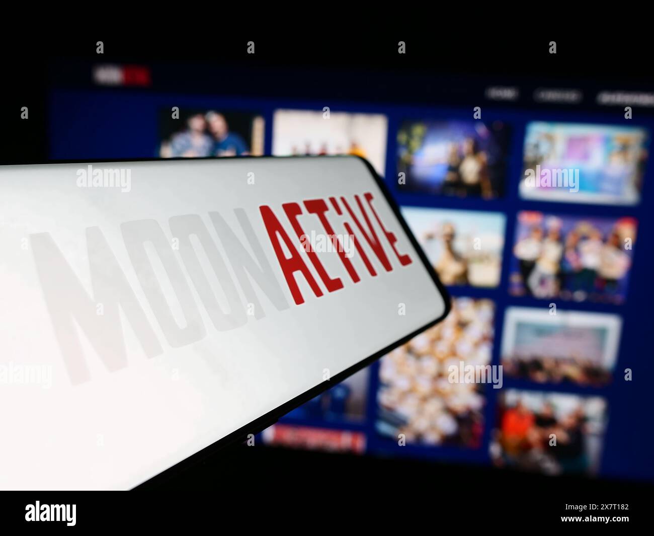 Mobile phone with logo of Israeli mobile games company Moon Active Ltd. in front of business ...