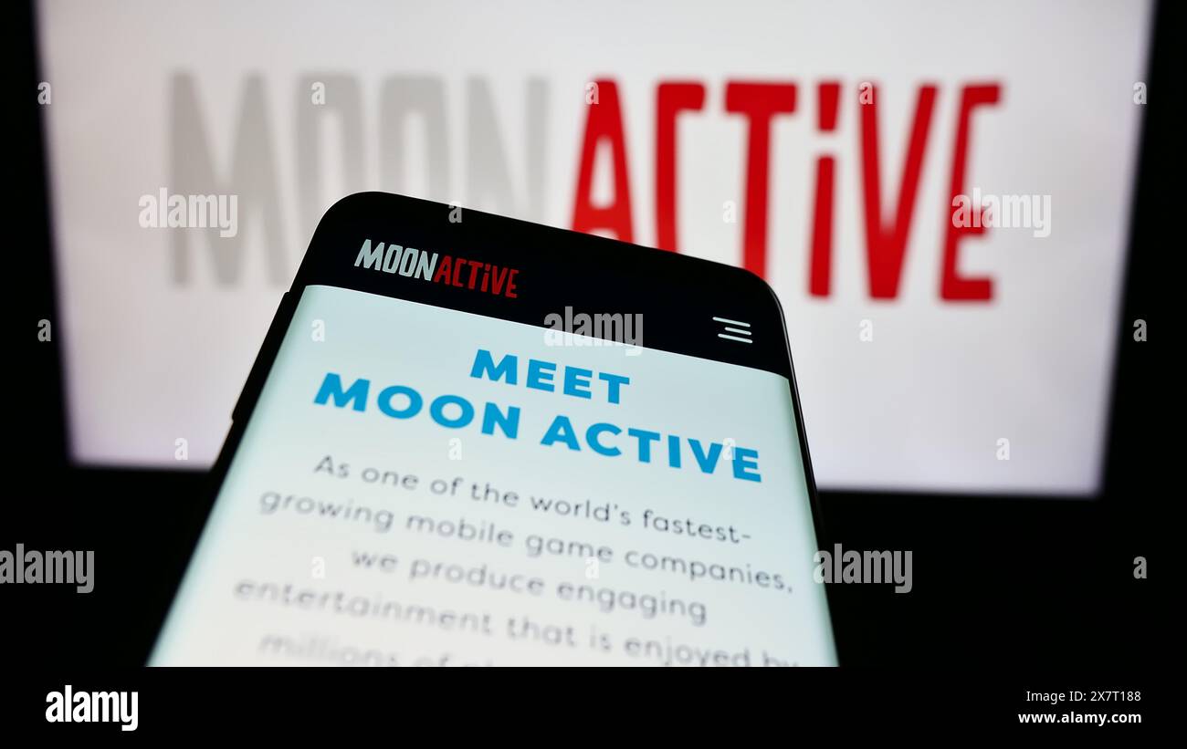 Smartphone with website of Israeli mobile games company Moon Active Ltd. in front of business ...