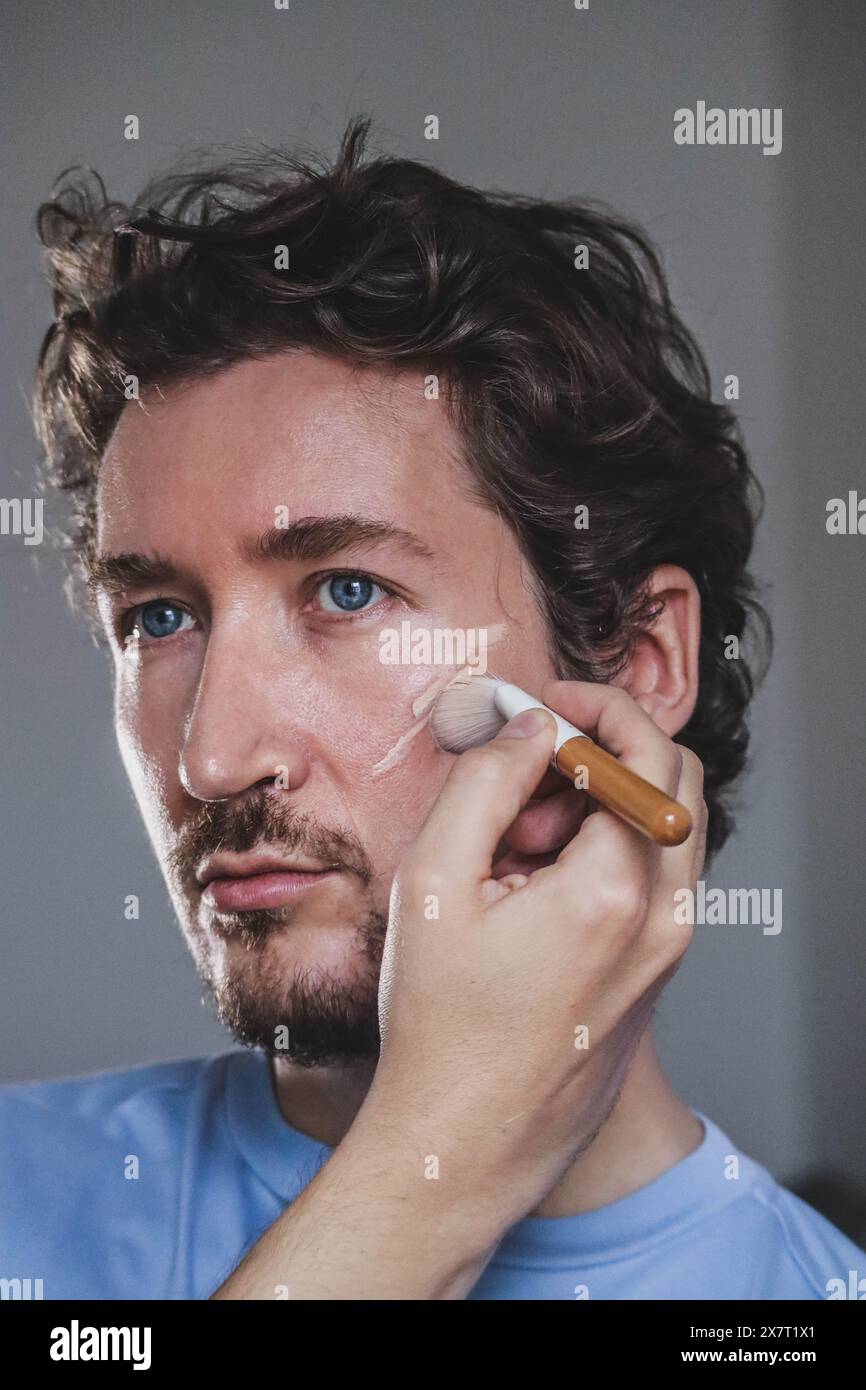 Handsome young man applying foundation to his face with a brush Stock ...