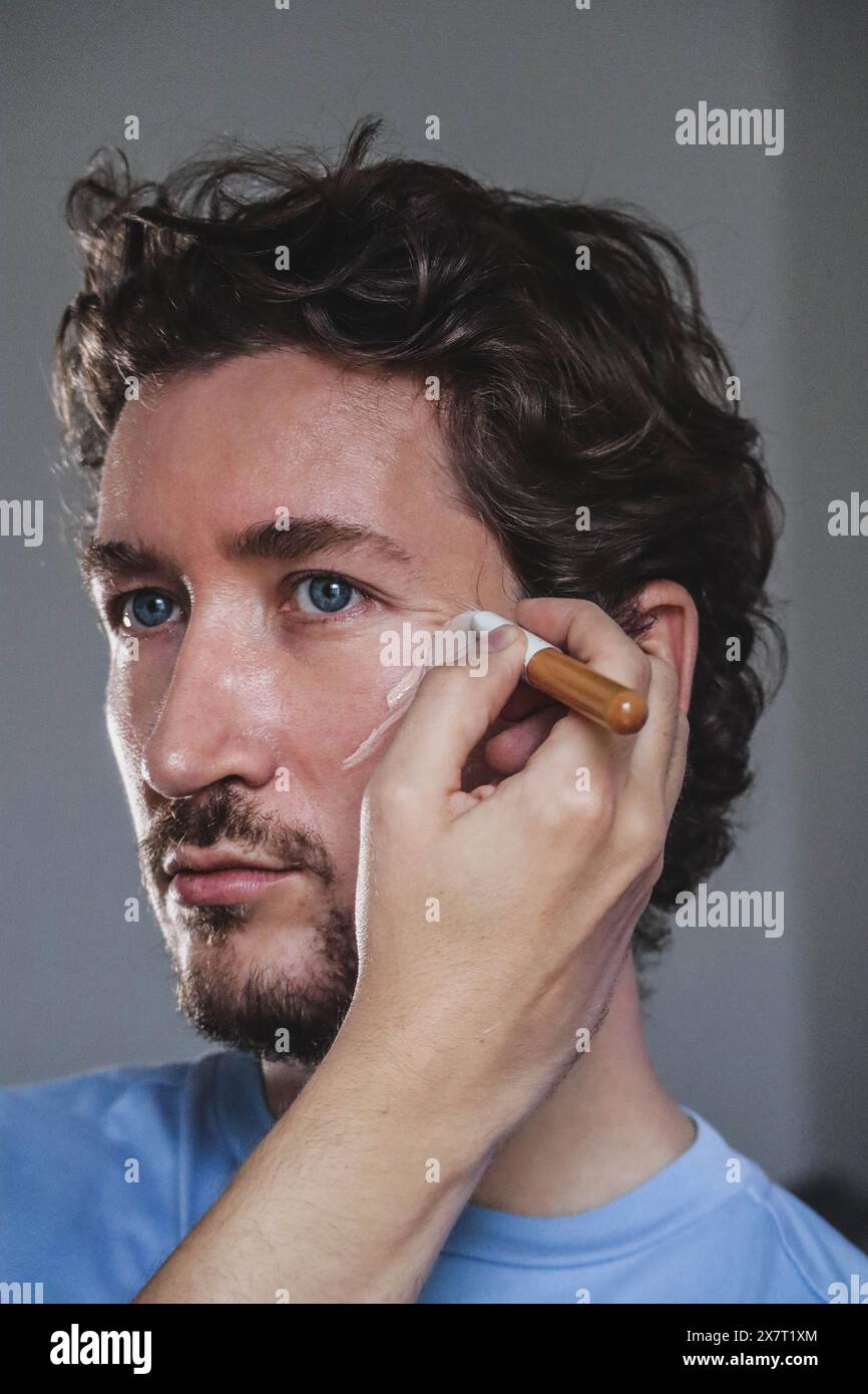 Handsome young man applying foundation to his face with a brush Stock ...