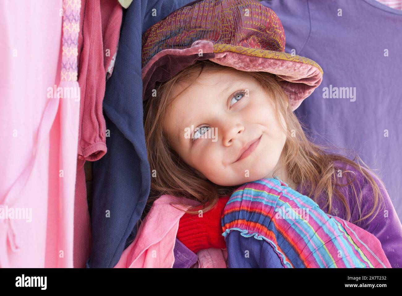 portrait of a cheerful little girl wearing a hat with piles of colorful ...