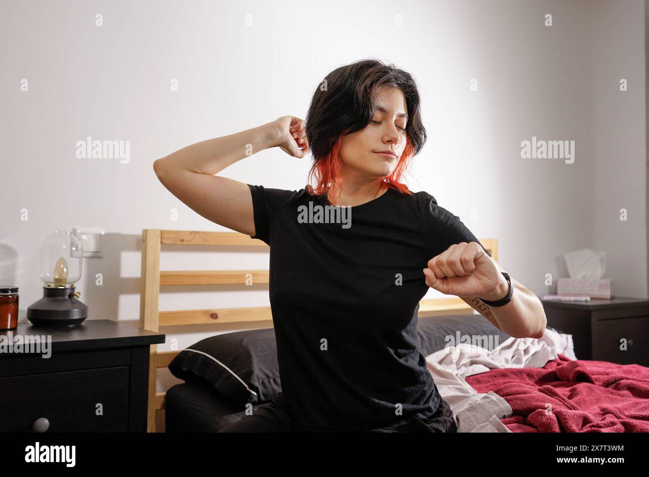 Black-haired white person stretching getting up from bed, starting ...