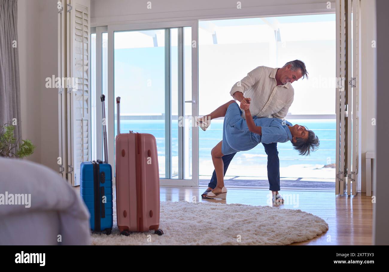 Mature Couple With Luggage Dancing In Beachfront House Overlooking ...