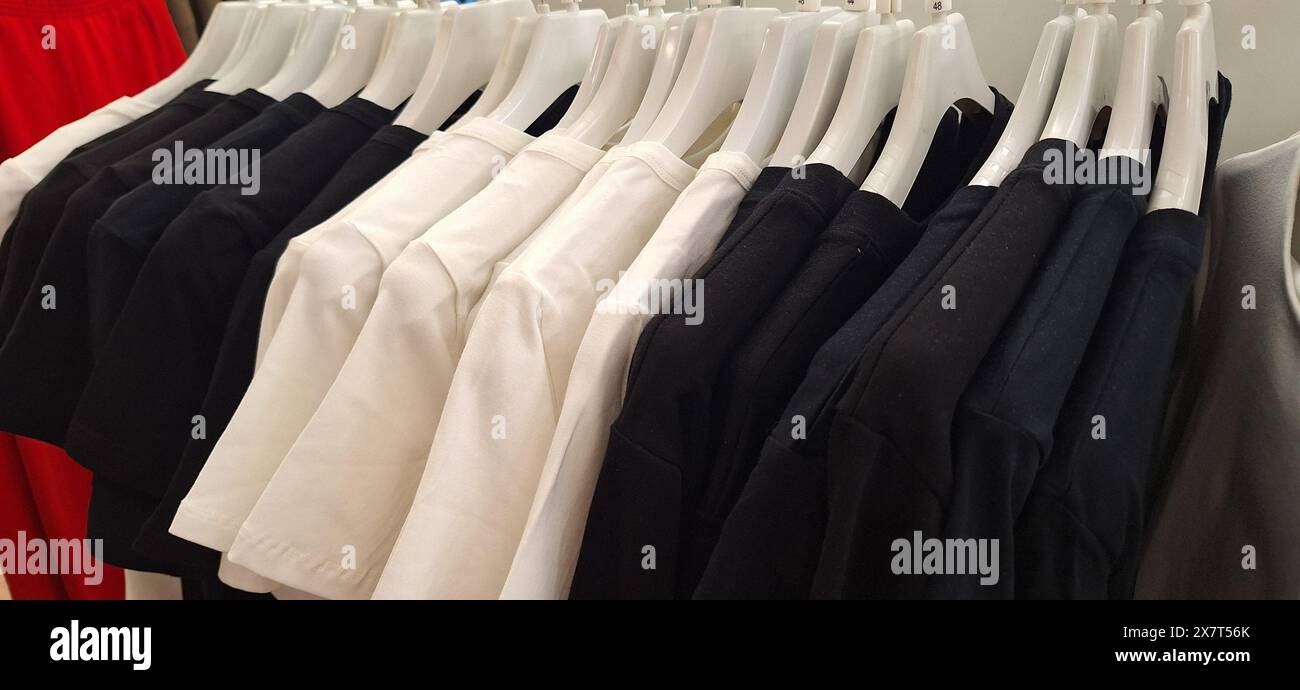 A rack filled with white and black pants hangs neatly on a wall ...