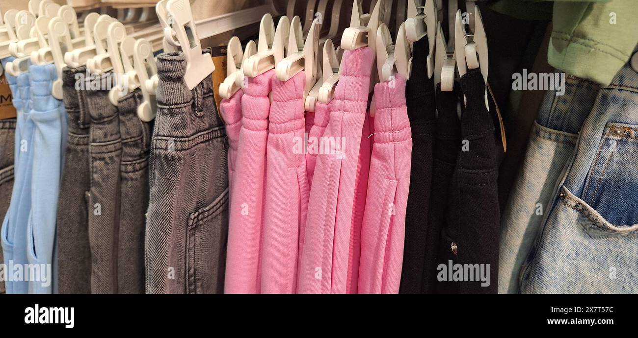 Different colored pants neatly hung on hooks in a rack. Variety of ...