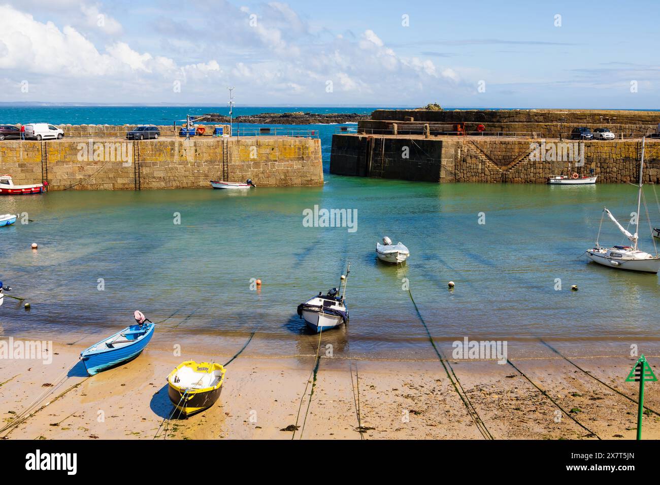 Boats in the harbour at mid tide, beach and mooring chains. The ...