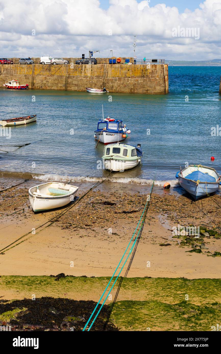 Boats in the harbour at mid tide, beach and mooring chains. The ...