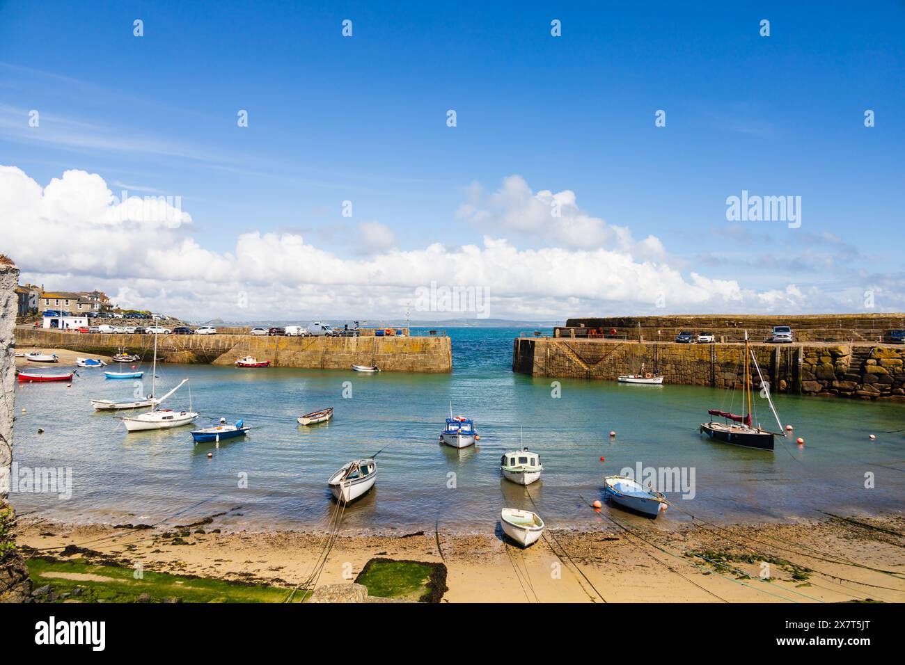 Boats in the harbour at mid tide, beach and mooring chains. The ...