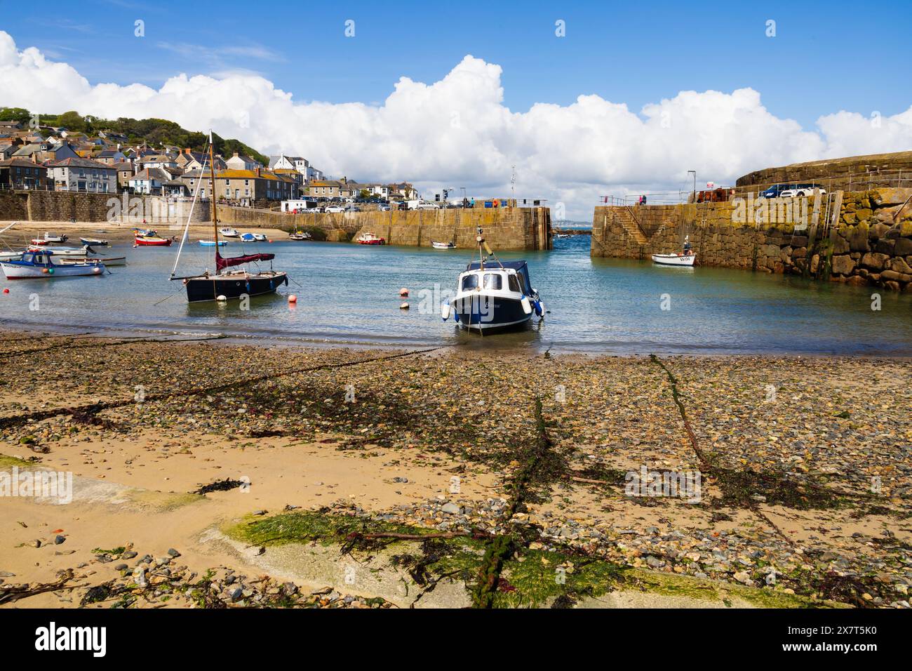 Boats in the harbour at mid tide, beach and mooring chains. The ...