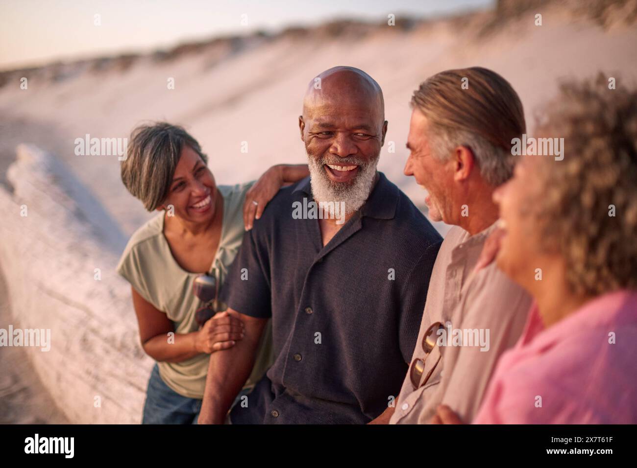 Mature Couple With Friends Sitting Outdoors On Beach Watching Sunset 6215