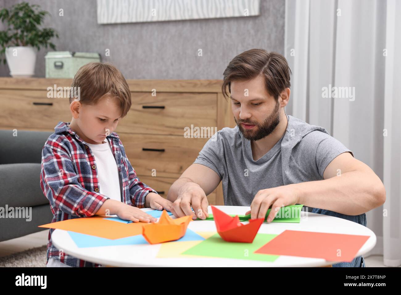 Dad and son making paper boats at coffee table indoors Stock Photo - Alamy