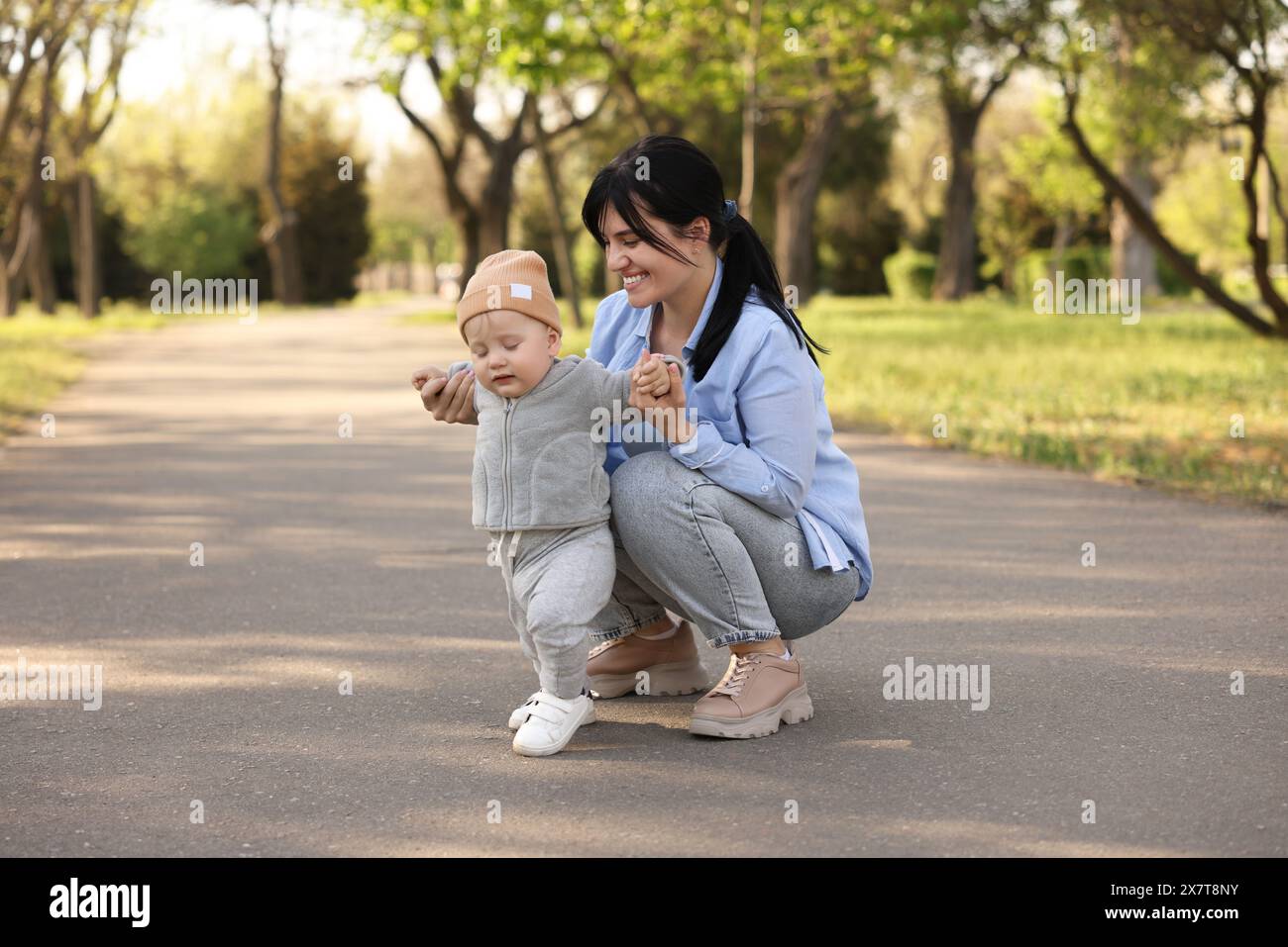 Mother supporting her baby while he learning to walk outdoors Stock ...