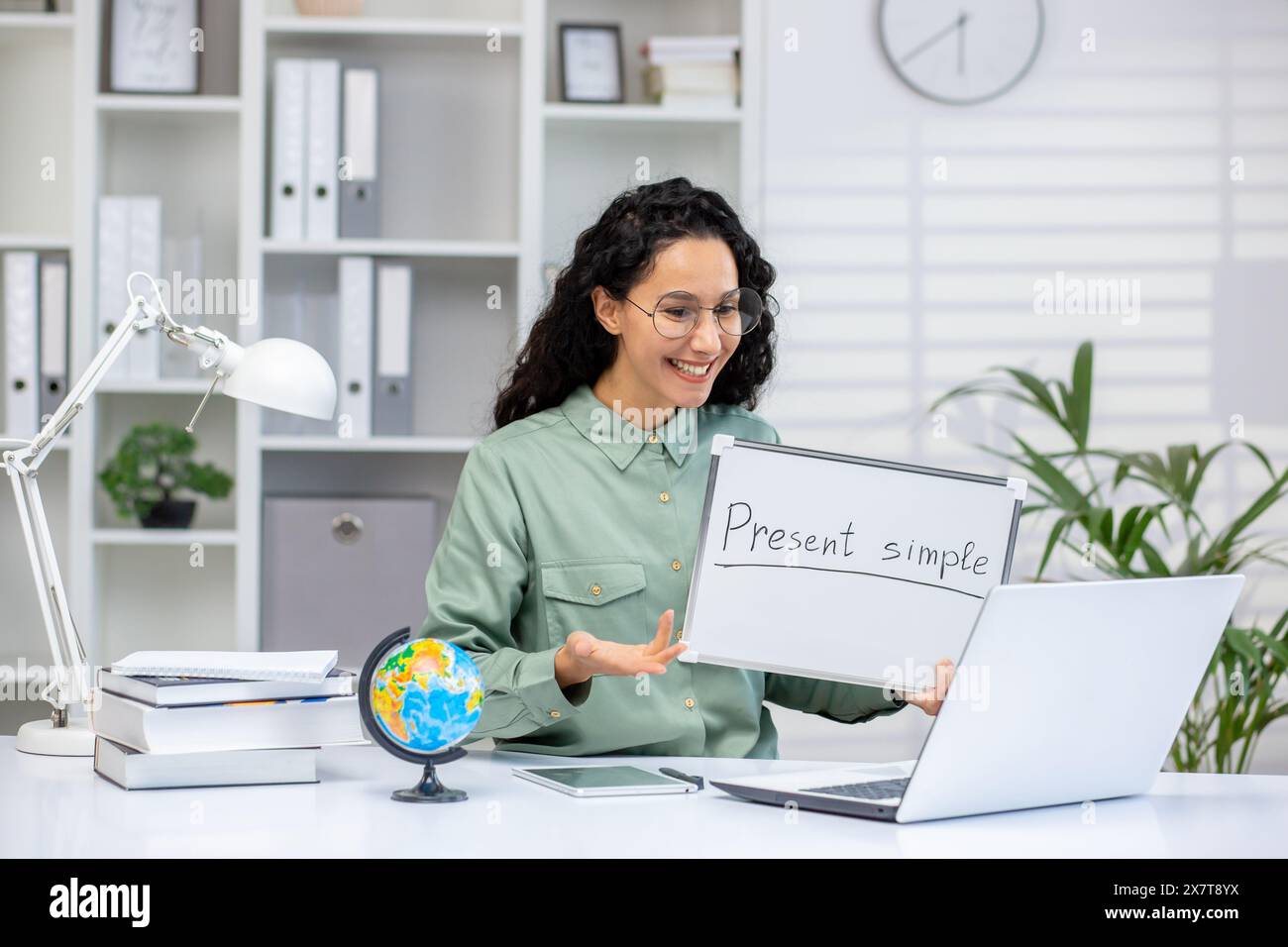 Smiling woman giving an online lesson using a whiteboard in a home ...