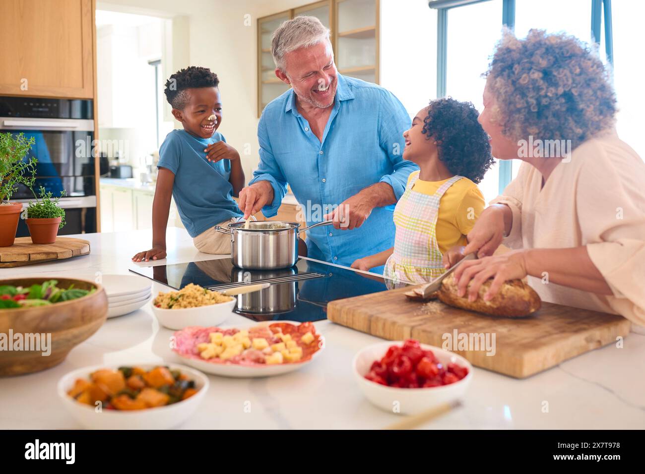 Grandchildren Helping Grandparents Prepare Meal In Kitchen At Home ...