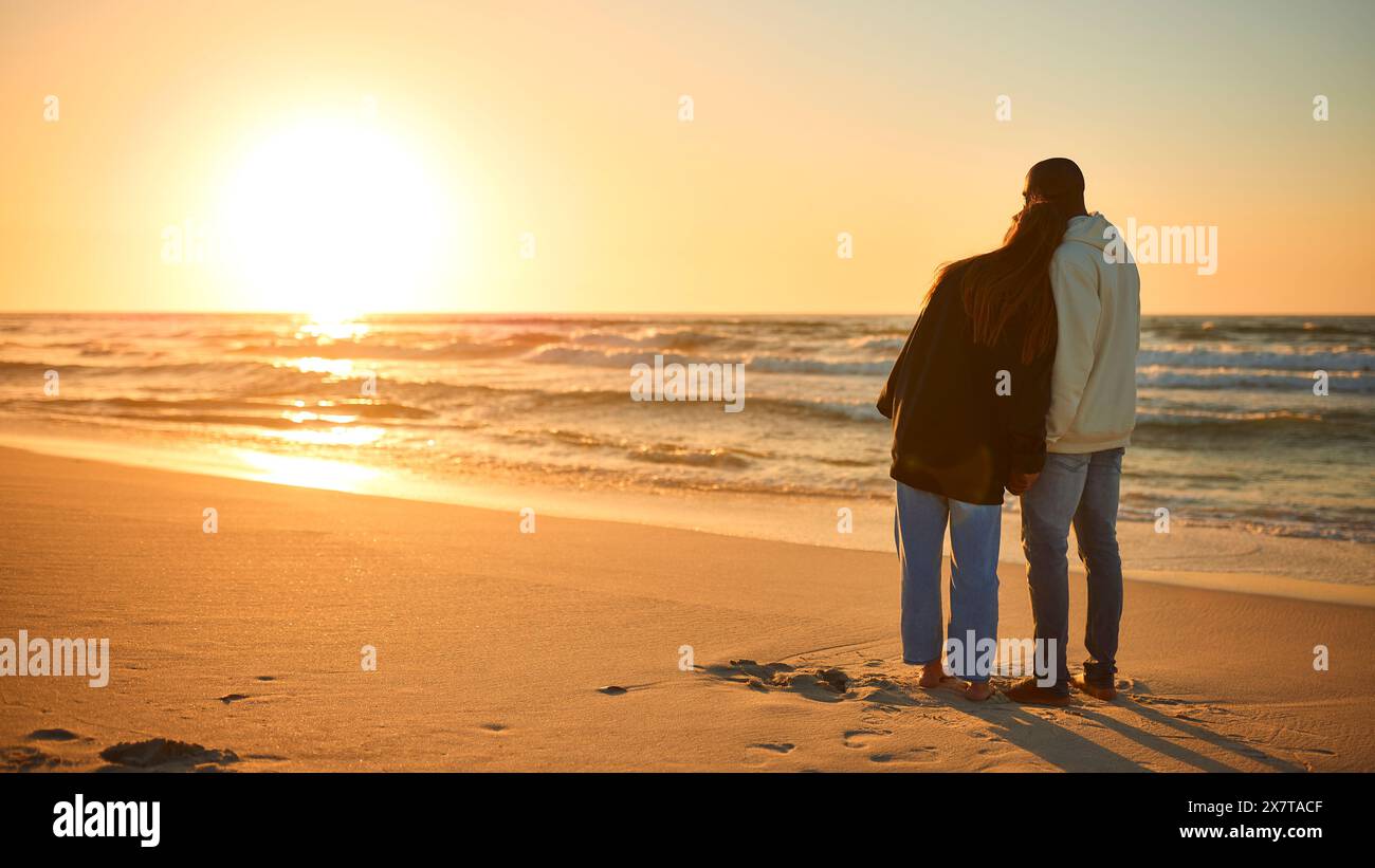 Rear View Of Casually Dressed Loving Young Couple Standing On Beach