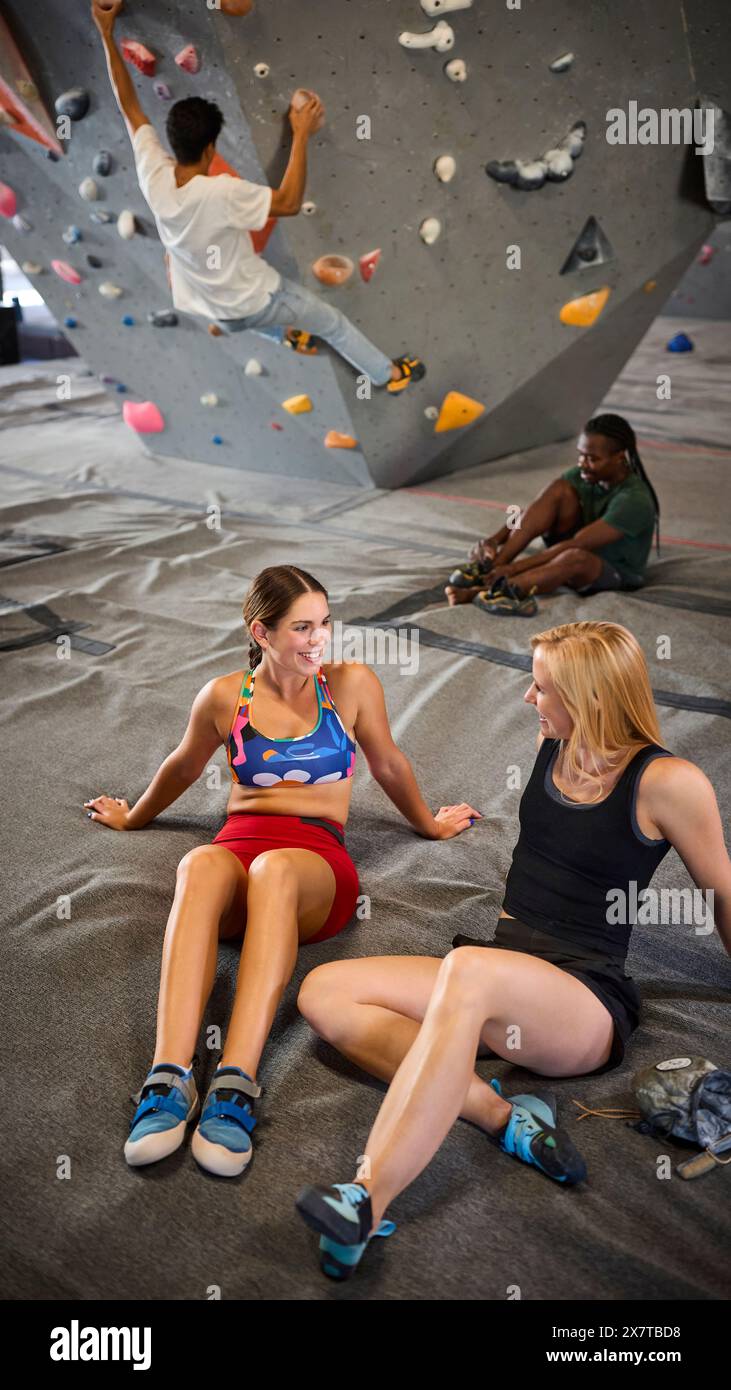 Two Women Taking A Break And Talking By Climbing Wall In Indoor ...