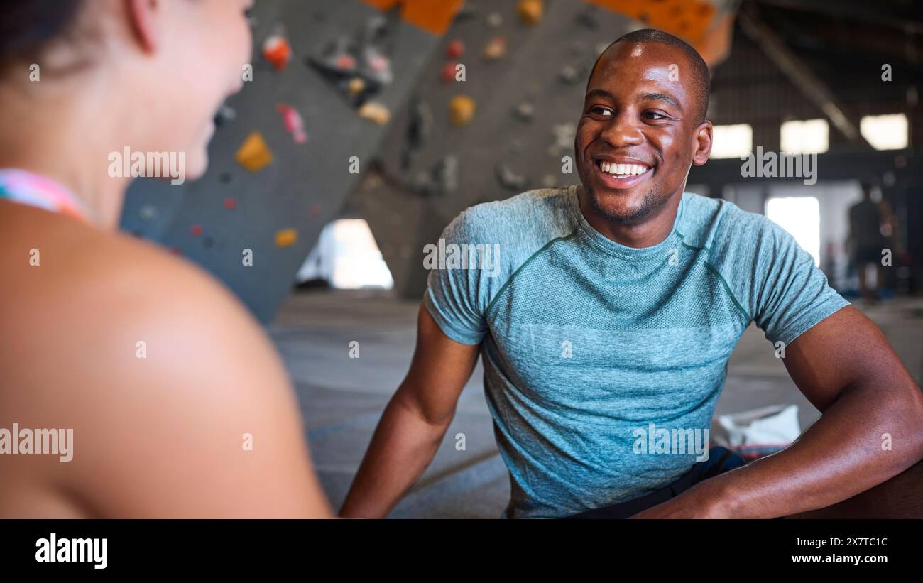 Male And Female Climbers Taking A Break And Talking By Climbing Wall In ...