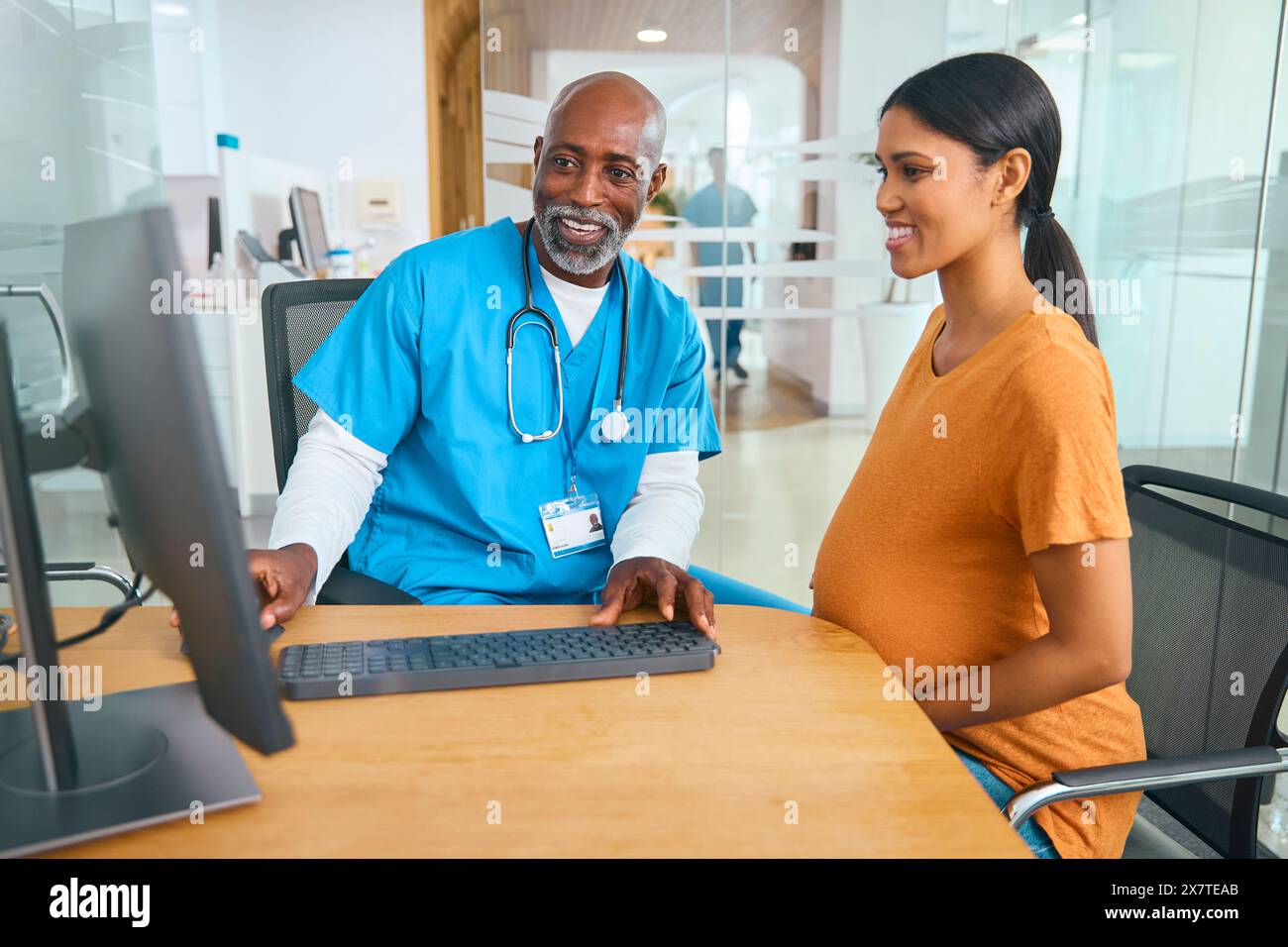 Male Nurse Or Doctor Wearing Scrubs With Pregnant Woman In Hospital ...