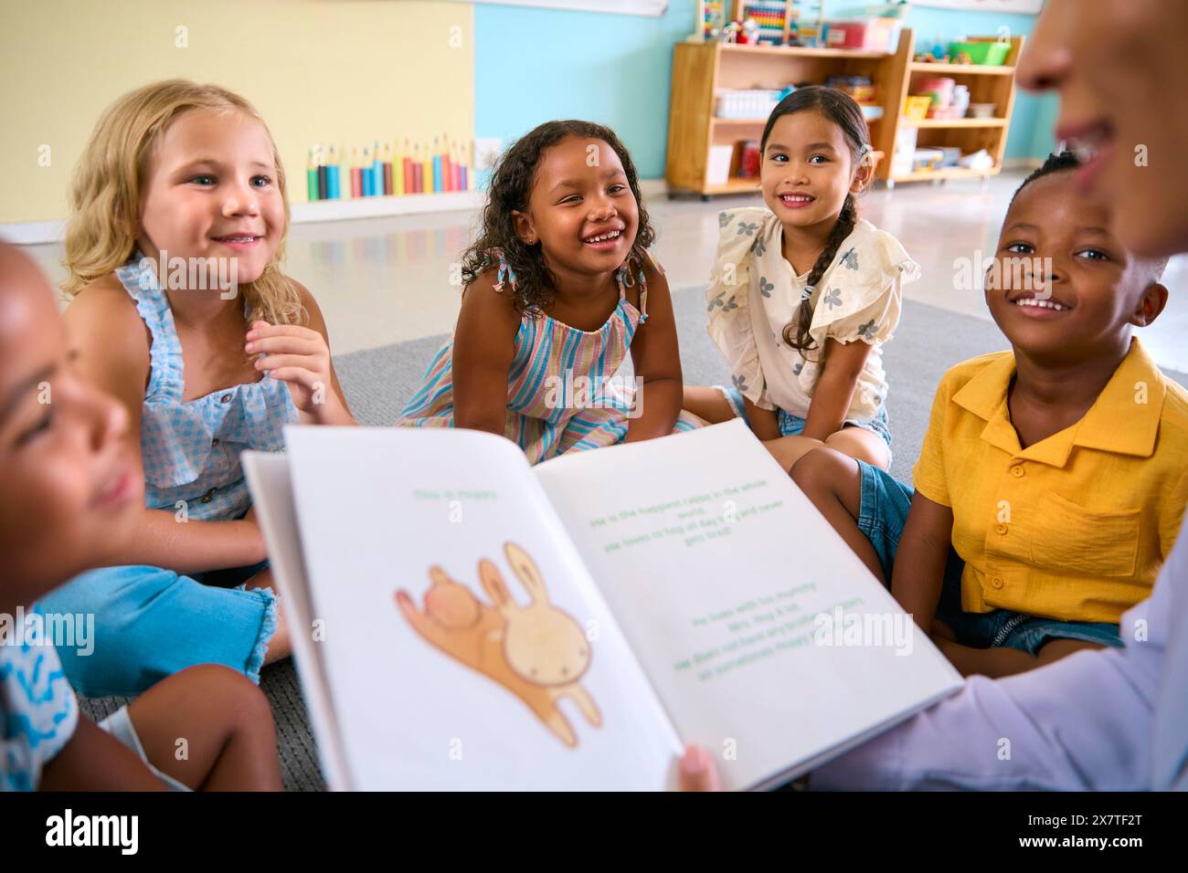 Female Primary Or Elementary School Teacher Reads Story To Multi ...