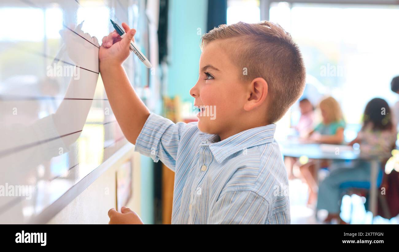 Male Primary Or Elementary School Student Writing On Whiteboard In ...