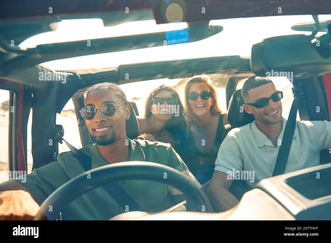 Young Couple With Friends On Vacation Inside Car Driving On Road Trip ...