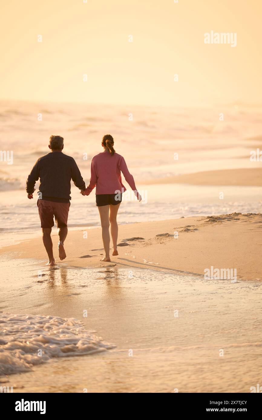 Rear View Of Retired Senior Couple On Vacation Running On Beach ...