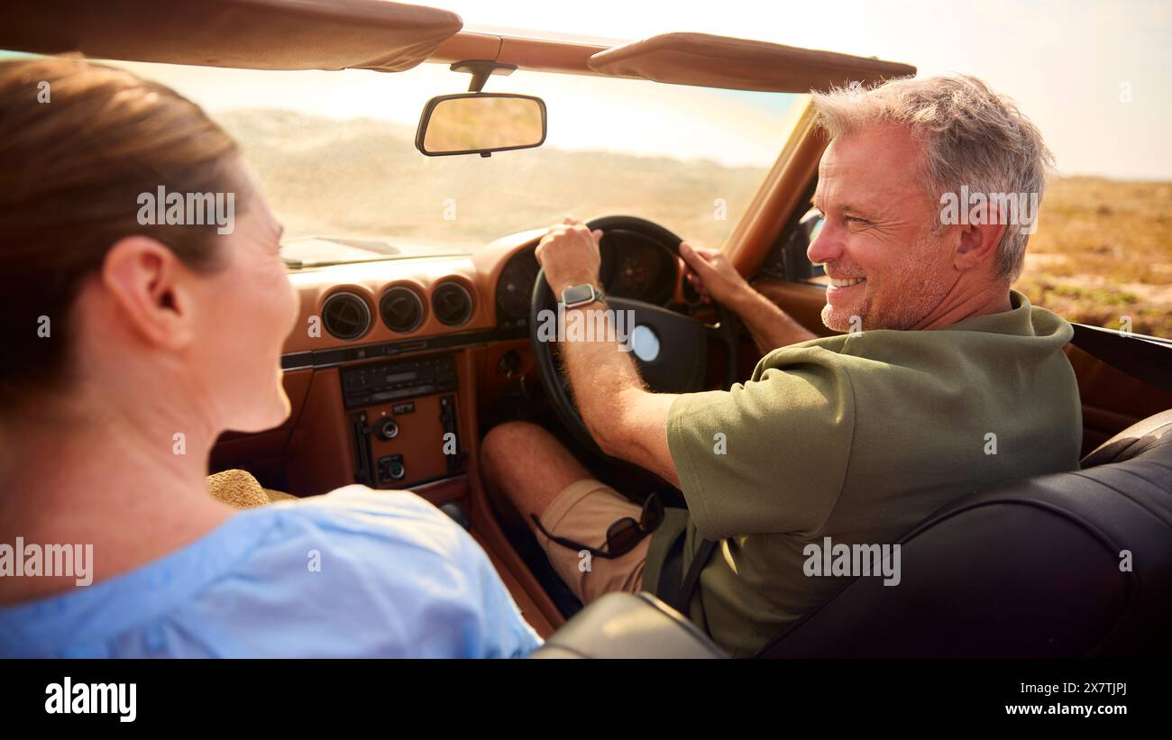 Retired Senior Couple On Vacation Driving In Classic Sports Car On Road ...