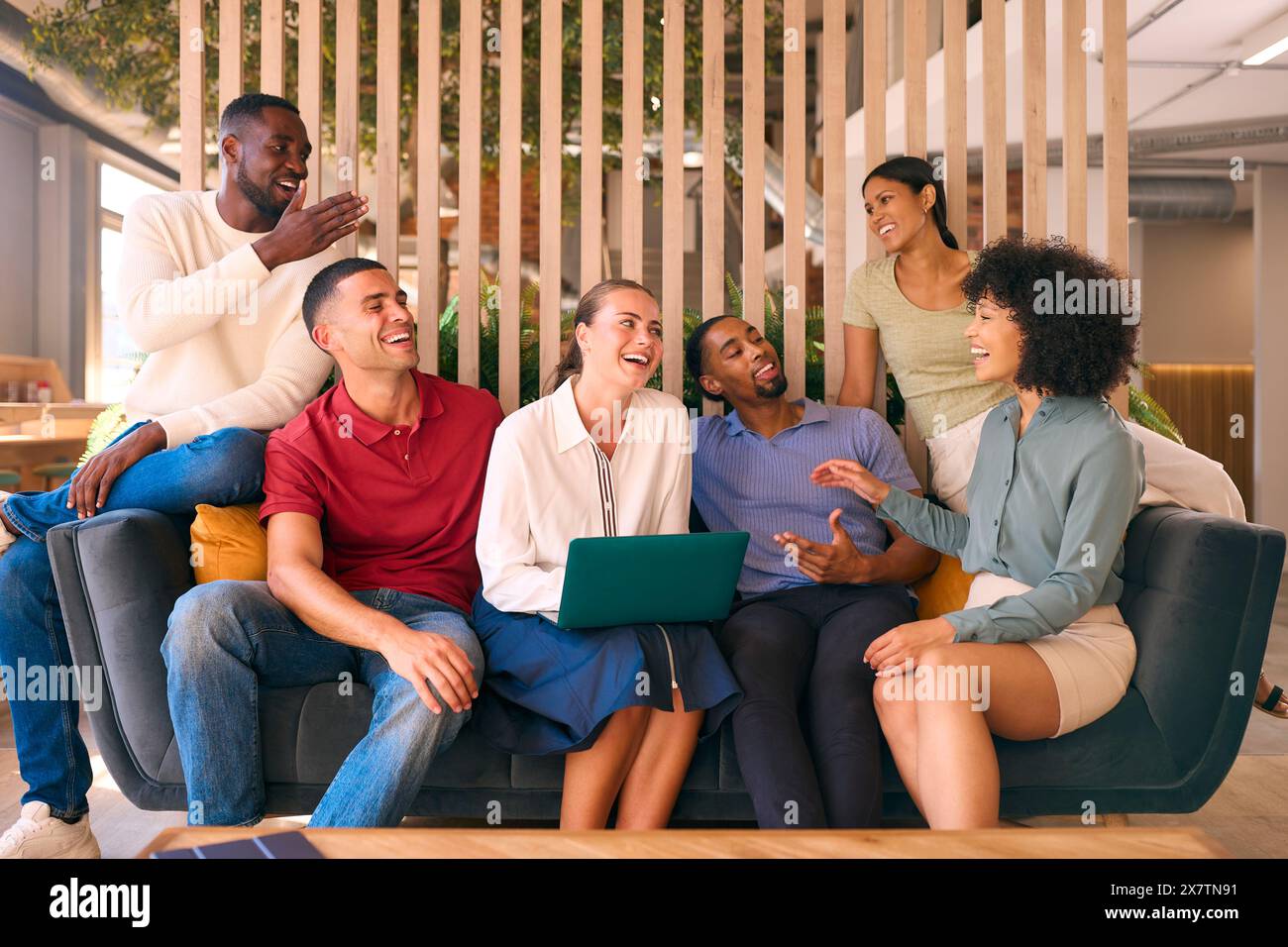 Multi-Cultural Business Team Sitting On Couch In Modern Open Plan ...