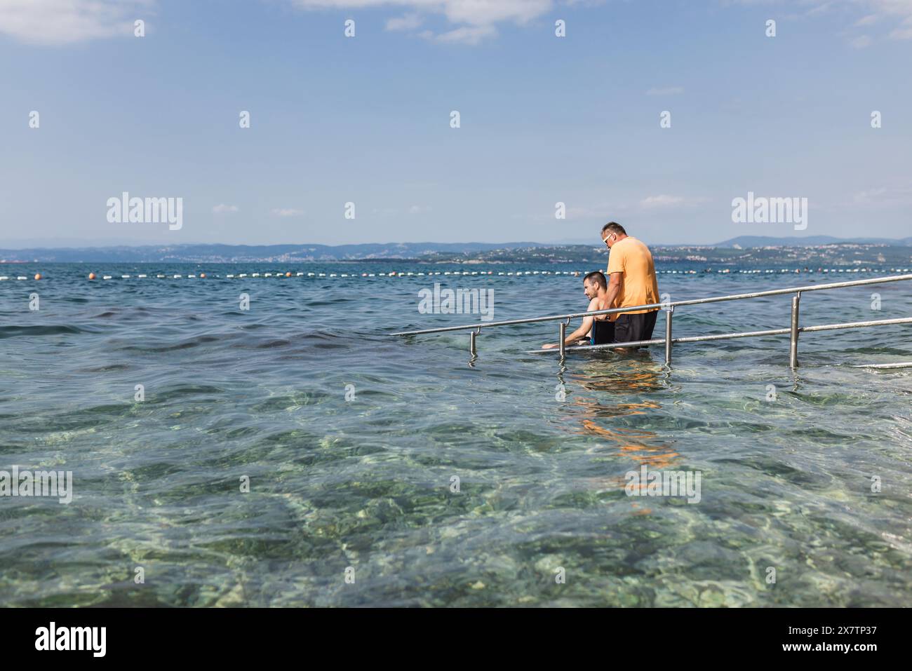 Wheelchair user entering the sea with the help of an assistant on ...