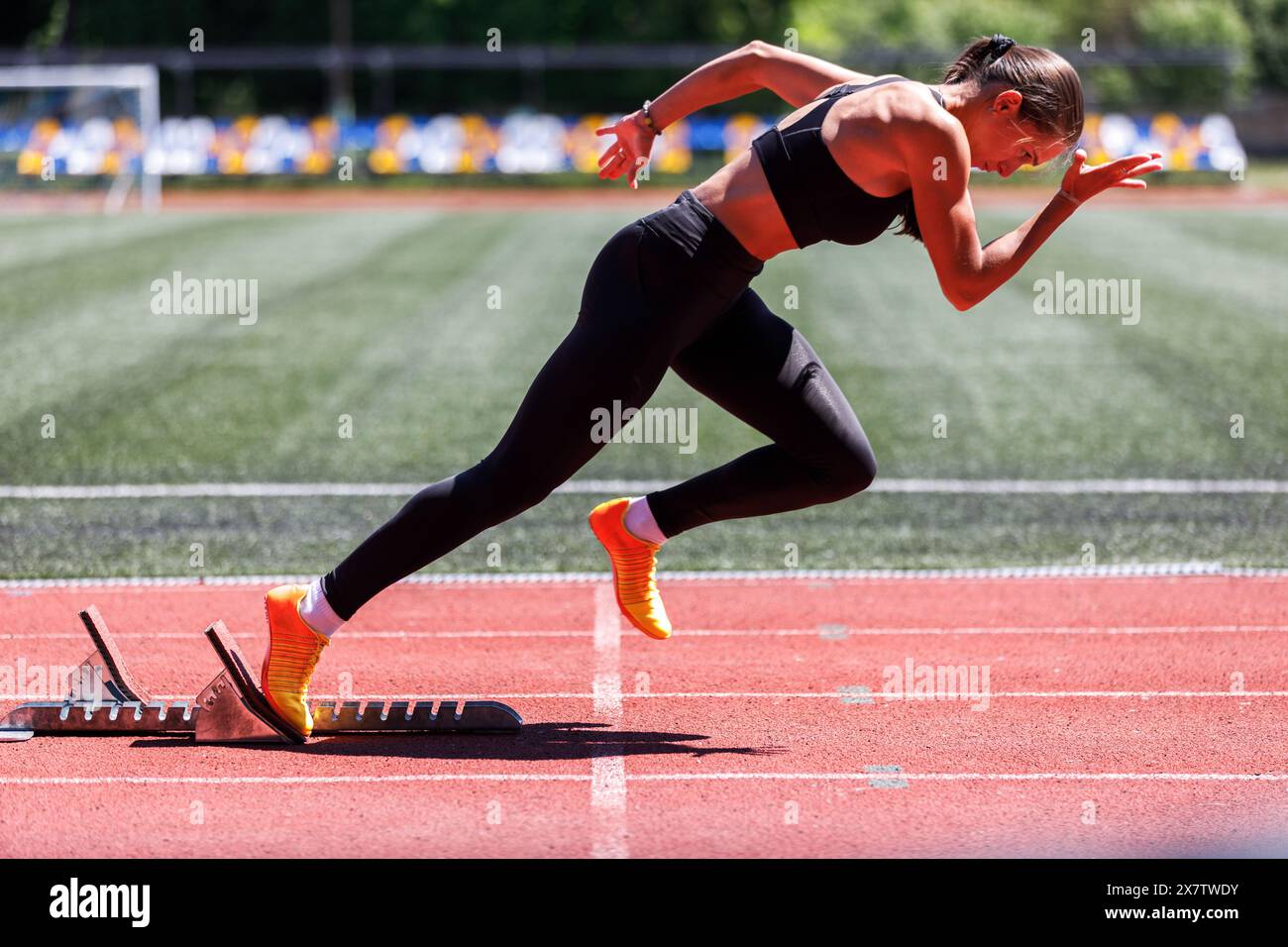 Young strong sprint sportswoman starting burst from starting blocks at ...