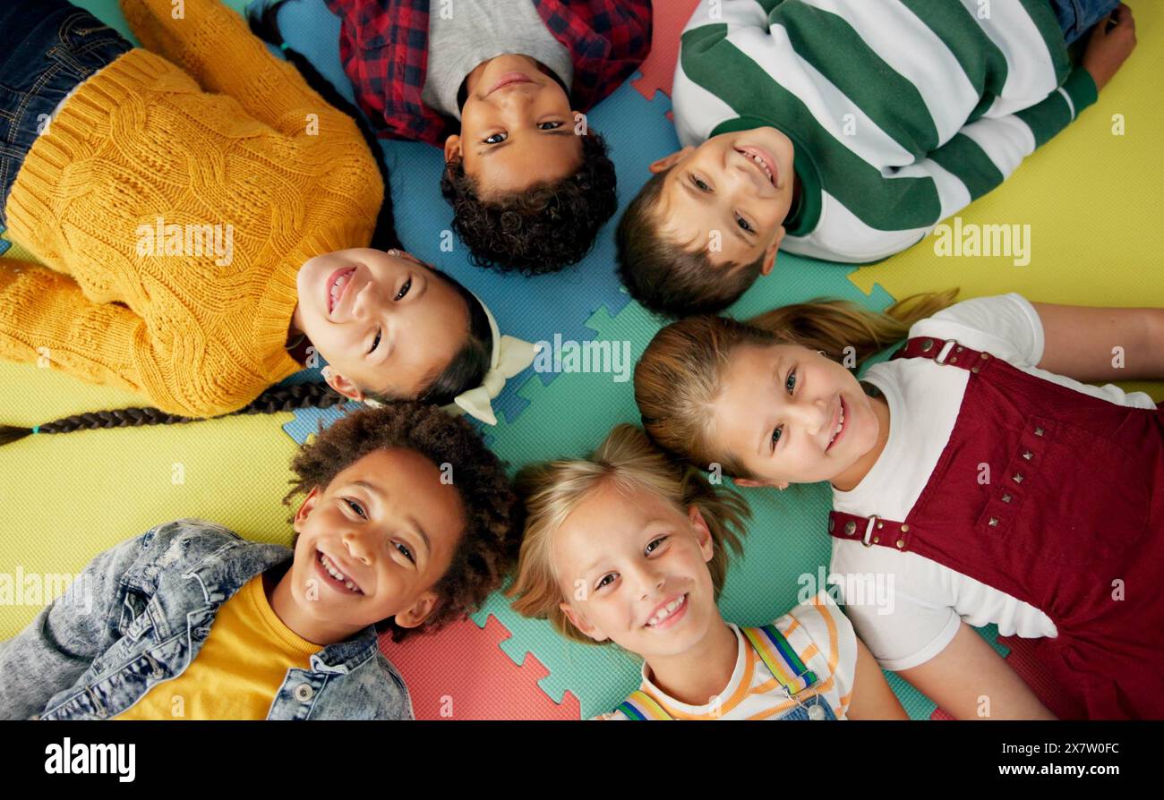 Happy, kids and laying in circle on mat in school with top view for ...