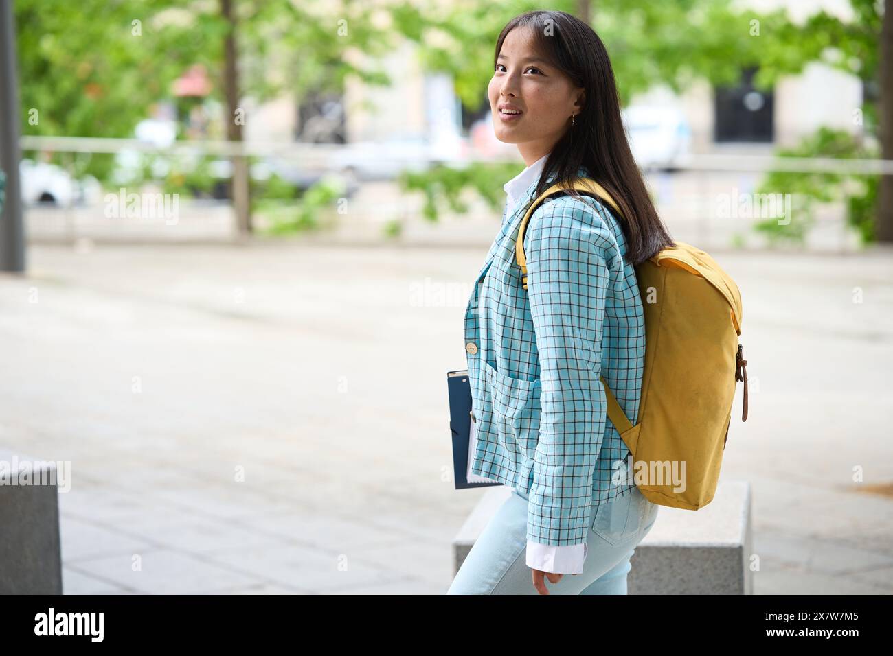 Chinese student wearing a blue jacket and yellow backpack is walking ...